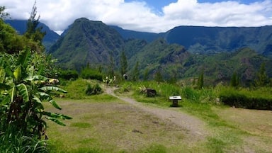 Paisagem montanhosa com céu limpo e uma trilha de terra que serpenteia em direção às montanhas.
