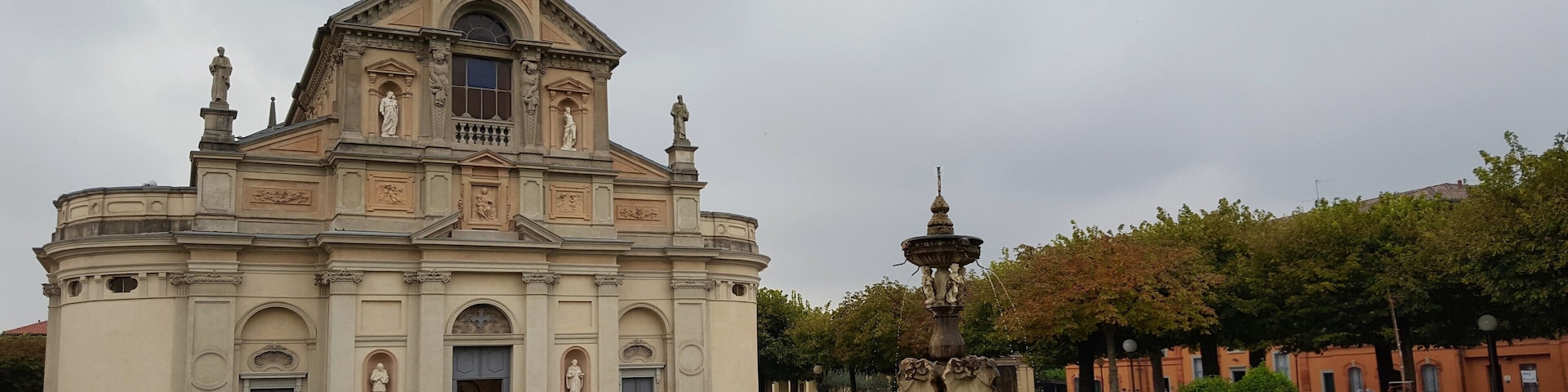 Uma igreja histórica com um campanário e uma fonte em primeiro plano.
