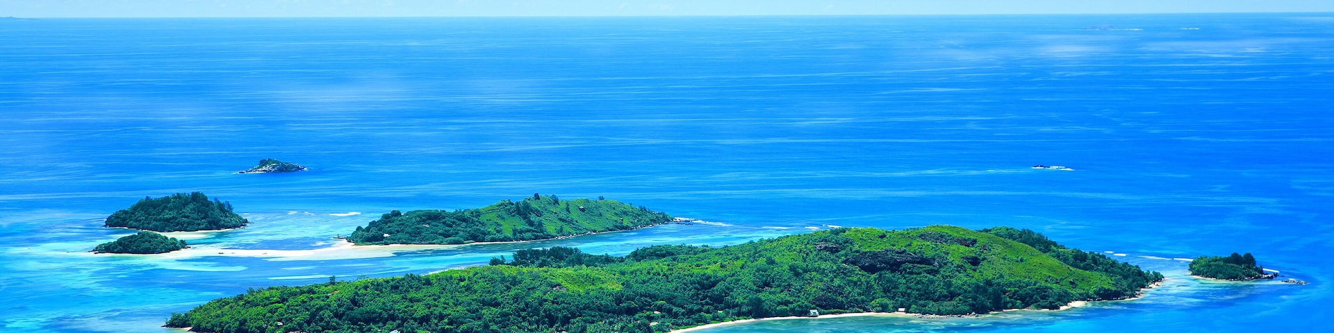Um arquipélago tropical com águas turquesa cristalinas e vegetação verde exuberante.