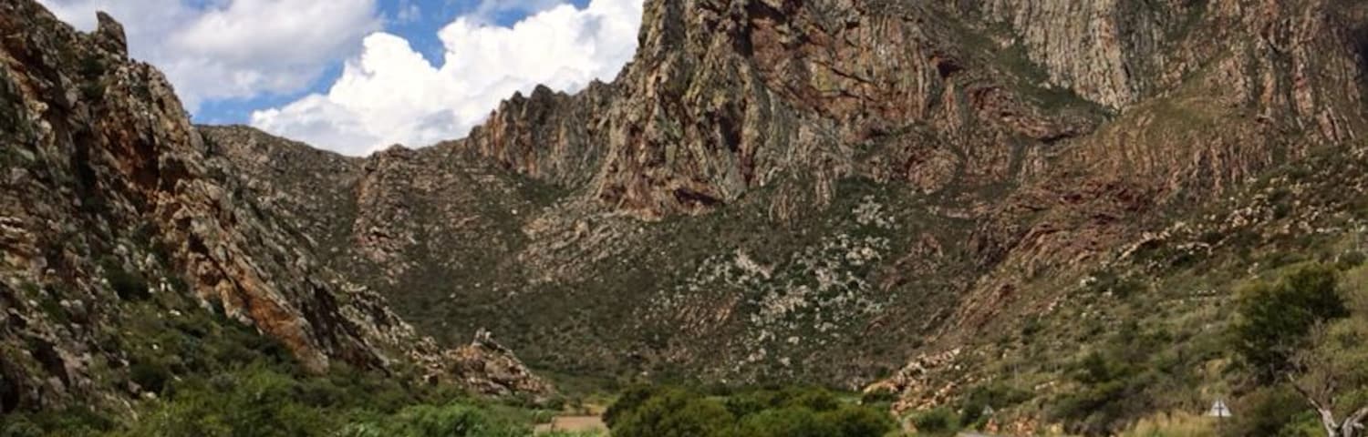Uma estrada sinuosa serpenteando por uma paisagem montanhosa, com penhascos rochosos e vegetação escassa.