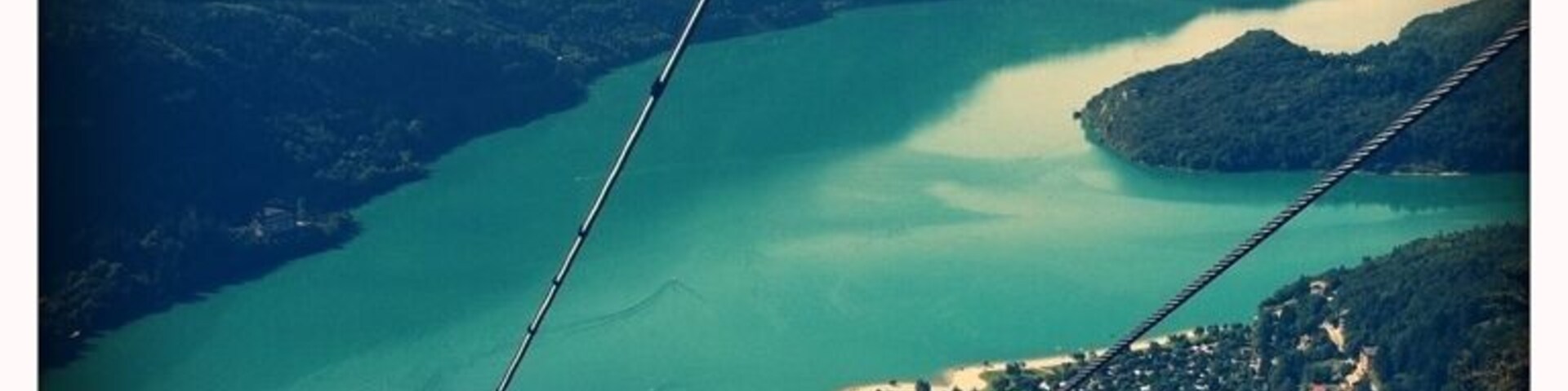 Teleférico com vista para um lago azul-turquesa e uma cidade situada no vale.