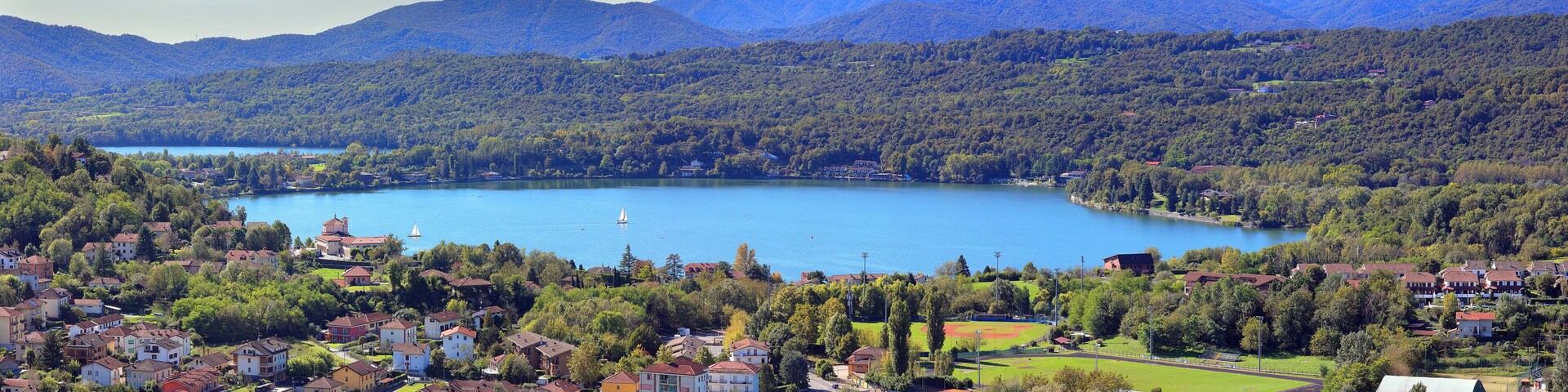 Um lago rodeado por montanhas e edifícios residenciais.