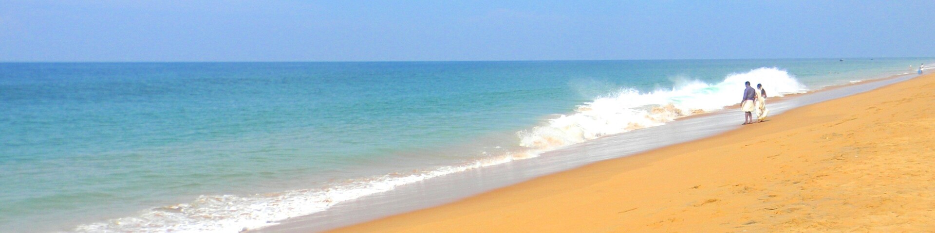 Uma praia arenosa com ondas suaves e céu claro.
