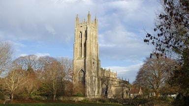 Uma igreja histórica com uma torre alta e um gramado bem cuidado em primeiro plano.