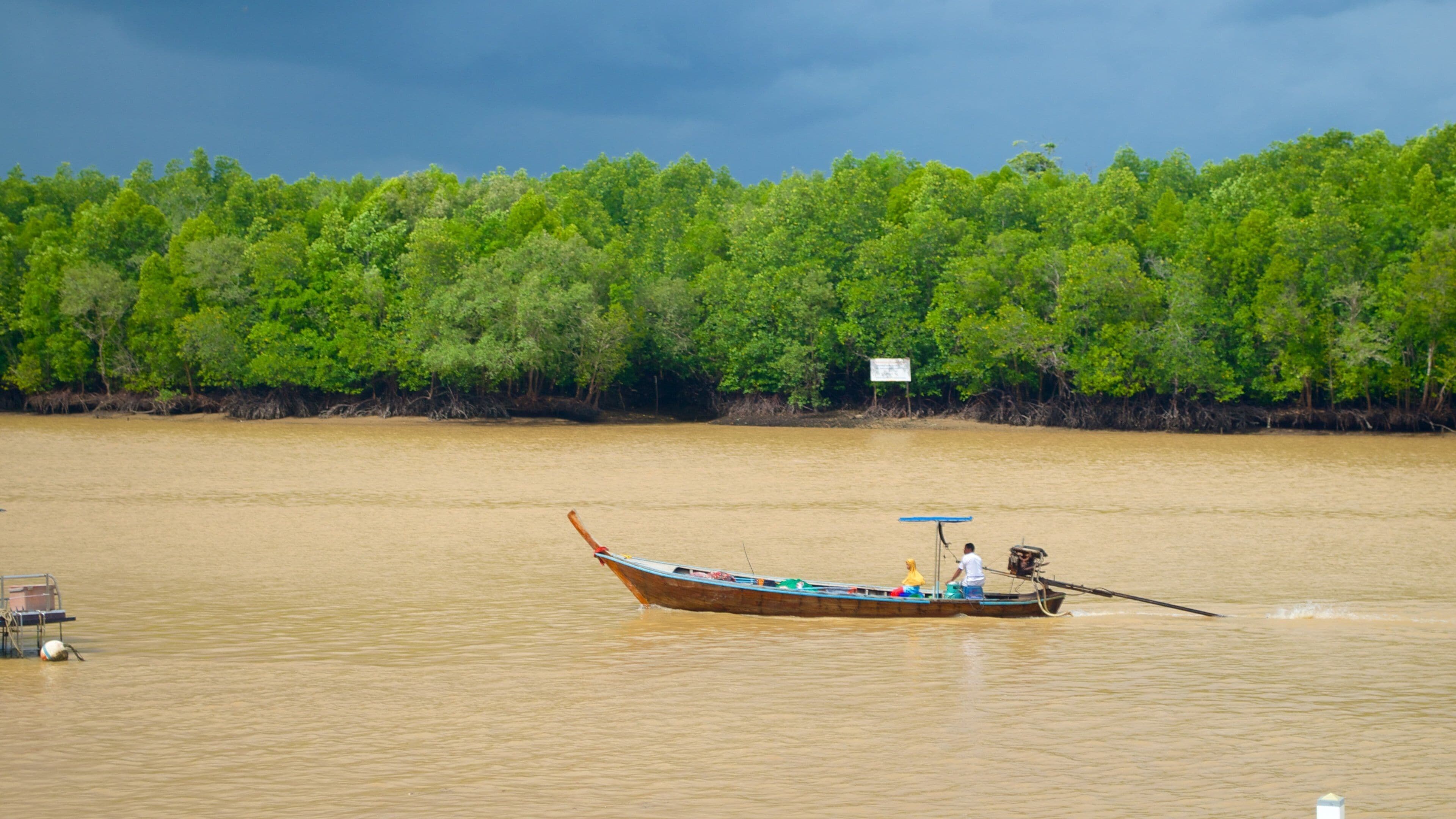 Um barco de cauda comprida em um rio calmo, com vegetação verde densa ao fundo.