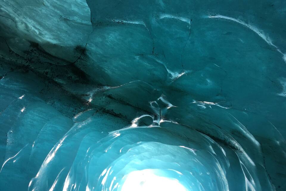 Uma caverna de gelo com rachaduras visíveis e uma luz brilhante no final.