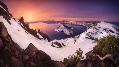 Cordilheira nevada com um lago e um pôr do sol.