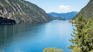 Um lago calmo rodeado por montanhas arborizadas sob um céu limpo.