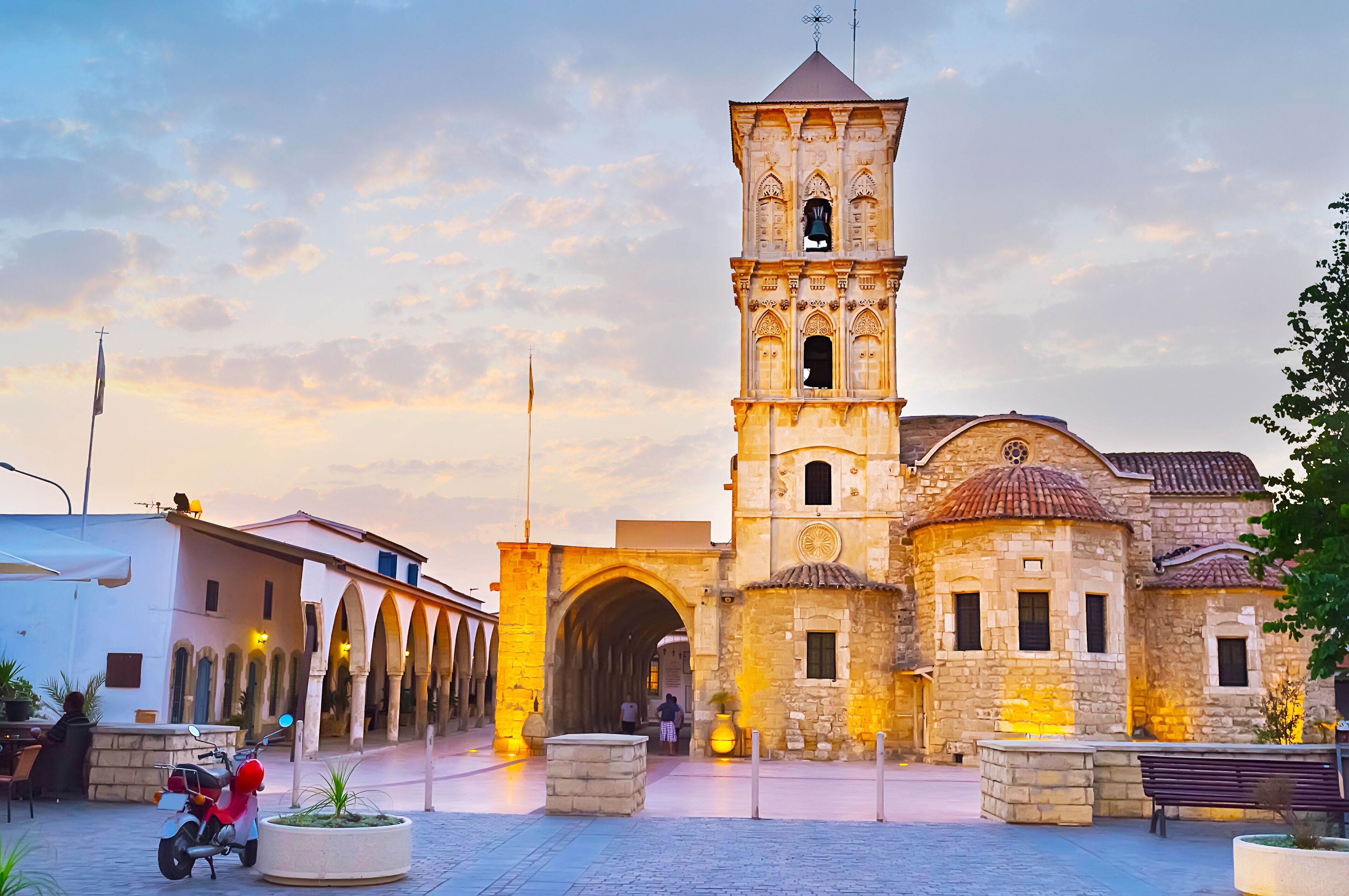 Um edifício histórico com uma torre de sino, arcos e um pátio.