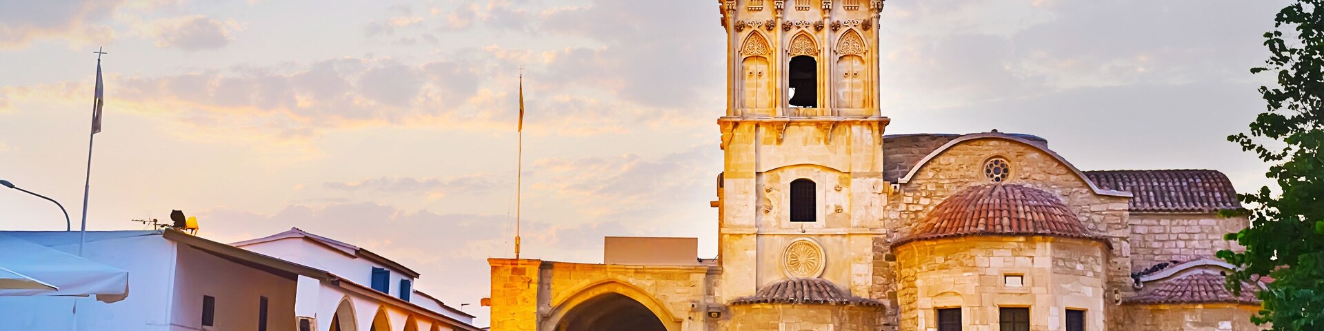 Um edifício histórico com uma torre de sino, arcos e um pátio.