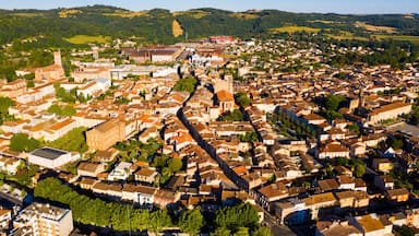 Uma cidade densamente povoada com edifícios históricos, uma igreja imponente e colinas ondulantes ao fundo.