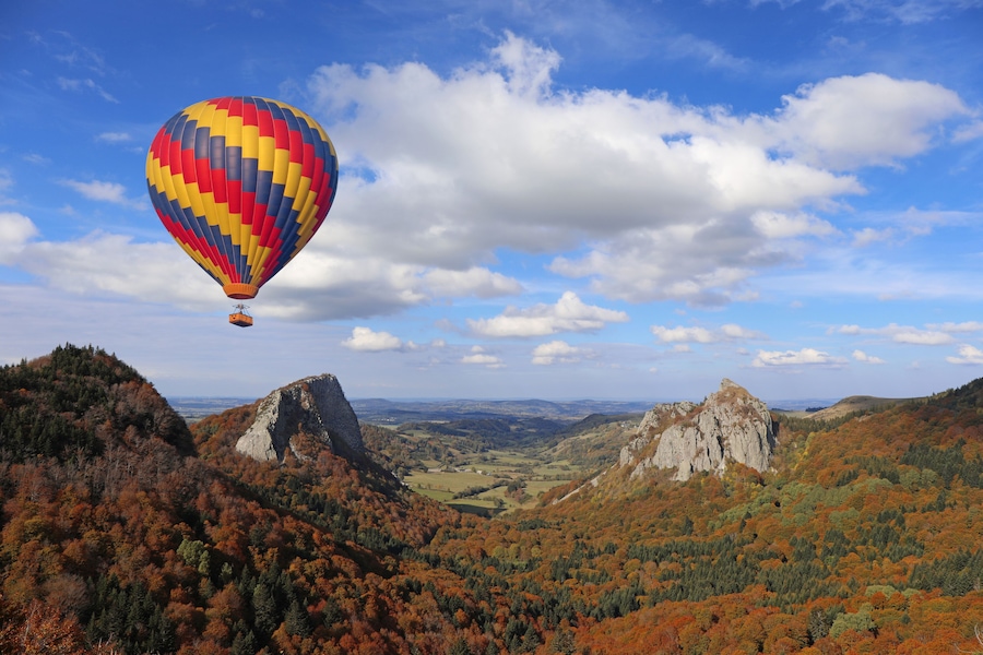 Um balão de ar quente sobre uma paisagem montanhosa com folhagem outonal.