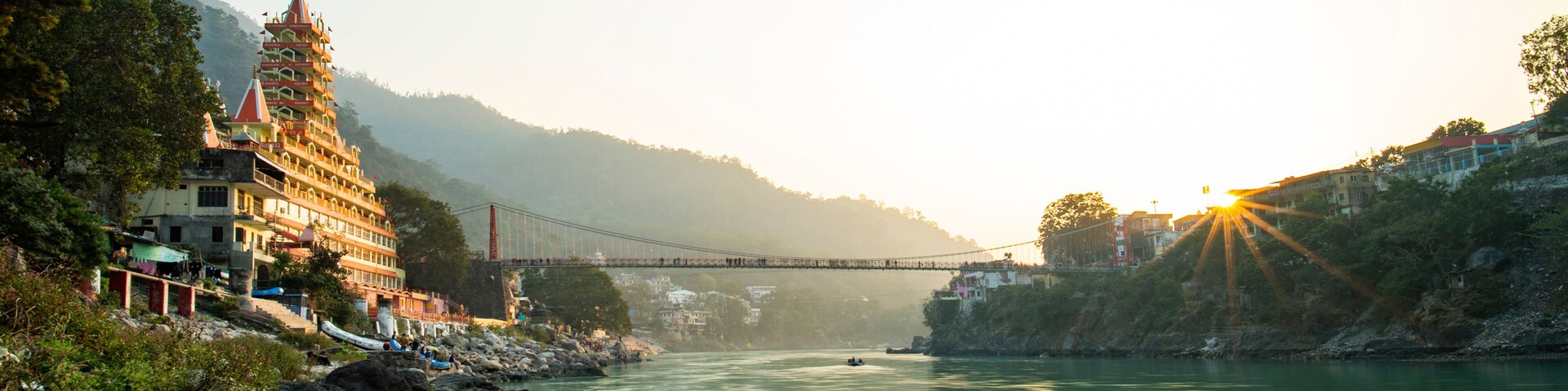 Um rio com uma ponte, um templo e uma montanha ao fundo.