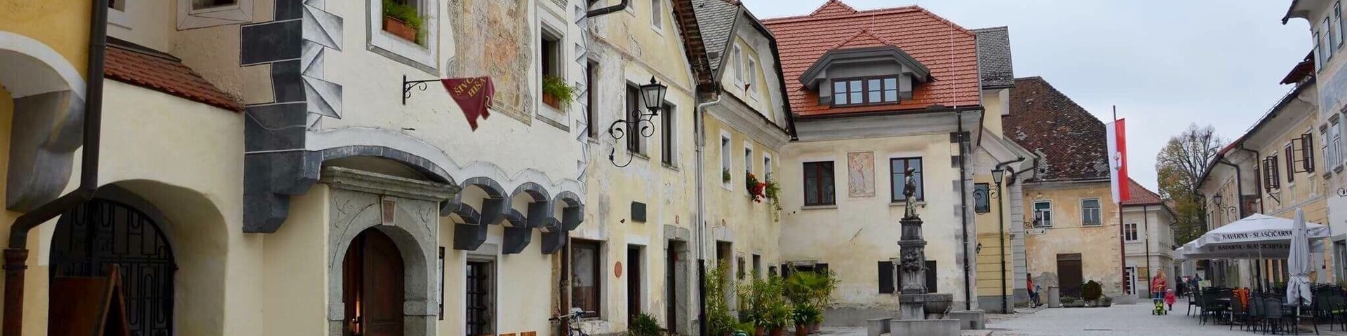 Uma rua de paralelepípedos ladeada por edifícios históricos, alguns com varandas e floreiras.