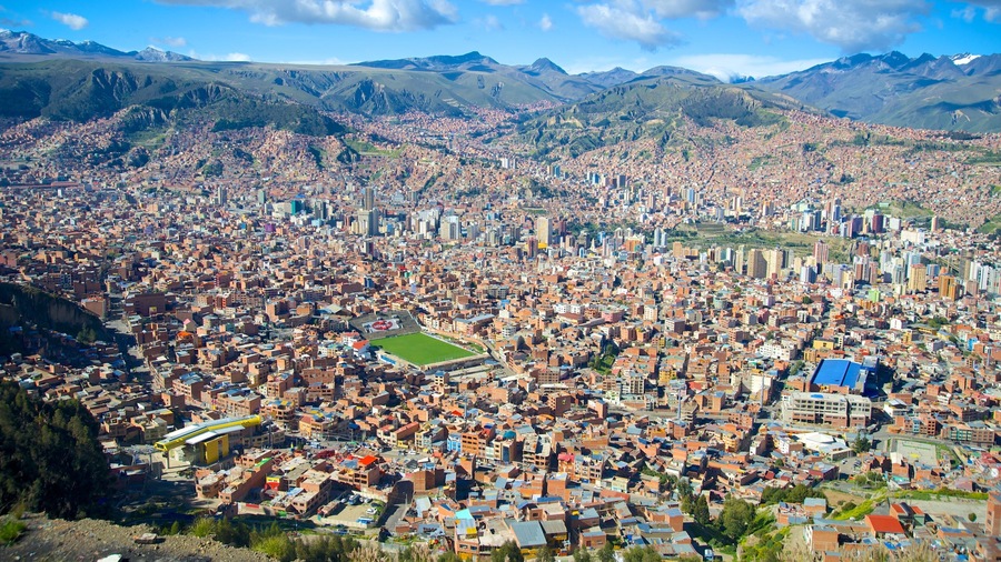 Uma cidade densamente povoada, com mistura de edifícios residenciais e comerciais, cercada por montanhas.