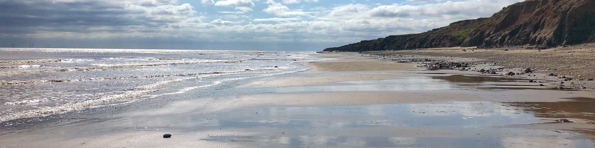 Uma praia com céu claro e ondas suaves.