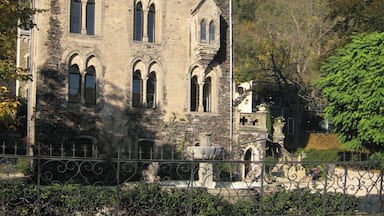 Um edifício histórico de pedra com janelas arqueadas e varanda vermelha.