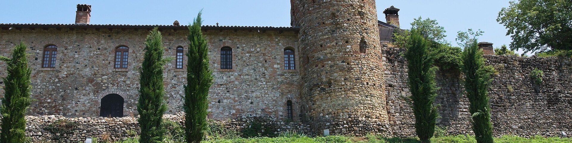 Um edifício histórico de pedra com uma torre imponente e janelas em arco.