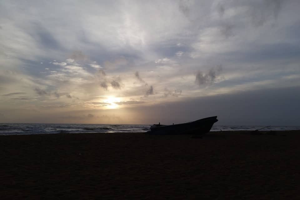 Uma praia com um barco e ondas sob um céu nublado.