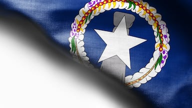 Uma bandeira com uma estrela branca e um emblema circular com contas coloridas.
