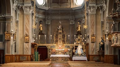 Interior de igreja ornamentado, com altar central, estátuas e um grande candelabro.