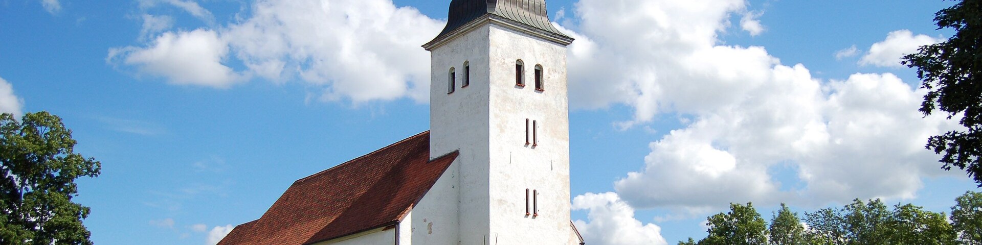 Uma igreja com uma torre alta e telhado vermelho.