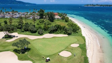 Um campo de golfe costeiro com praia e oceano.