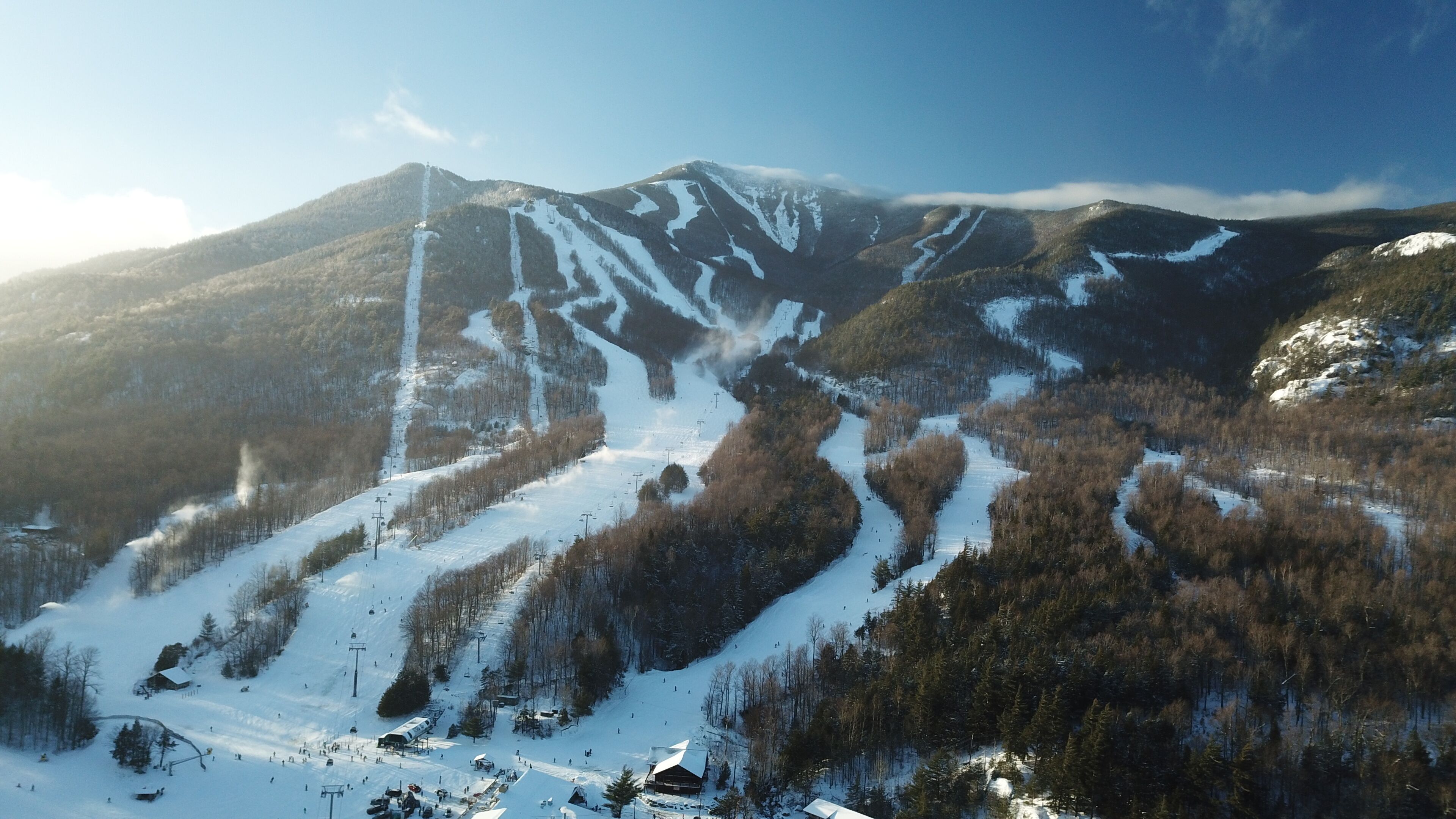 Montanha coberta de neve com pistas de esqui e um teleférico.
