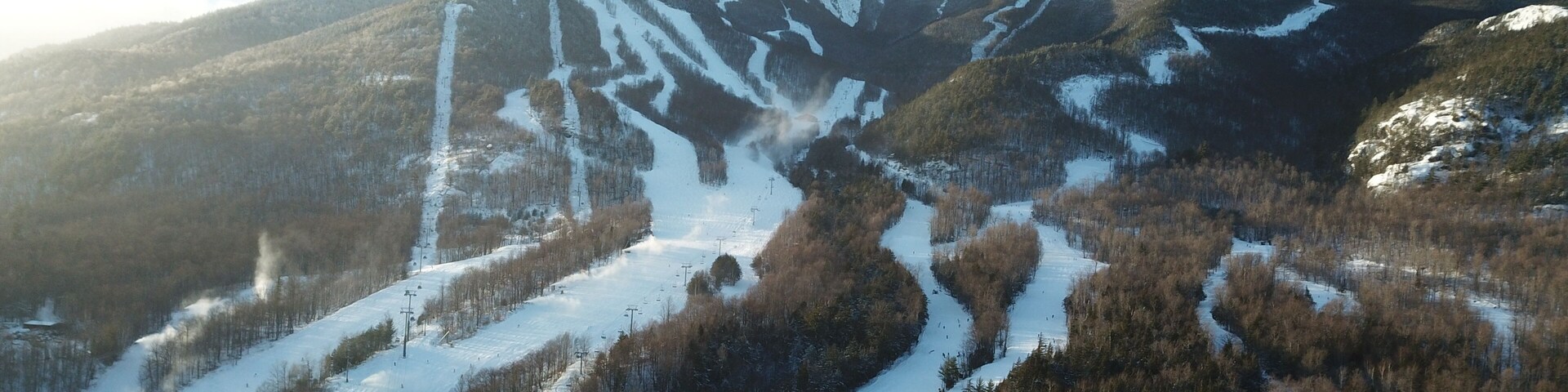 Montanha coberta de neve com pistas de esqui e um teleférico.