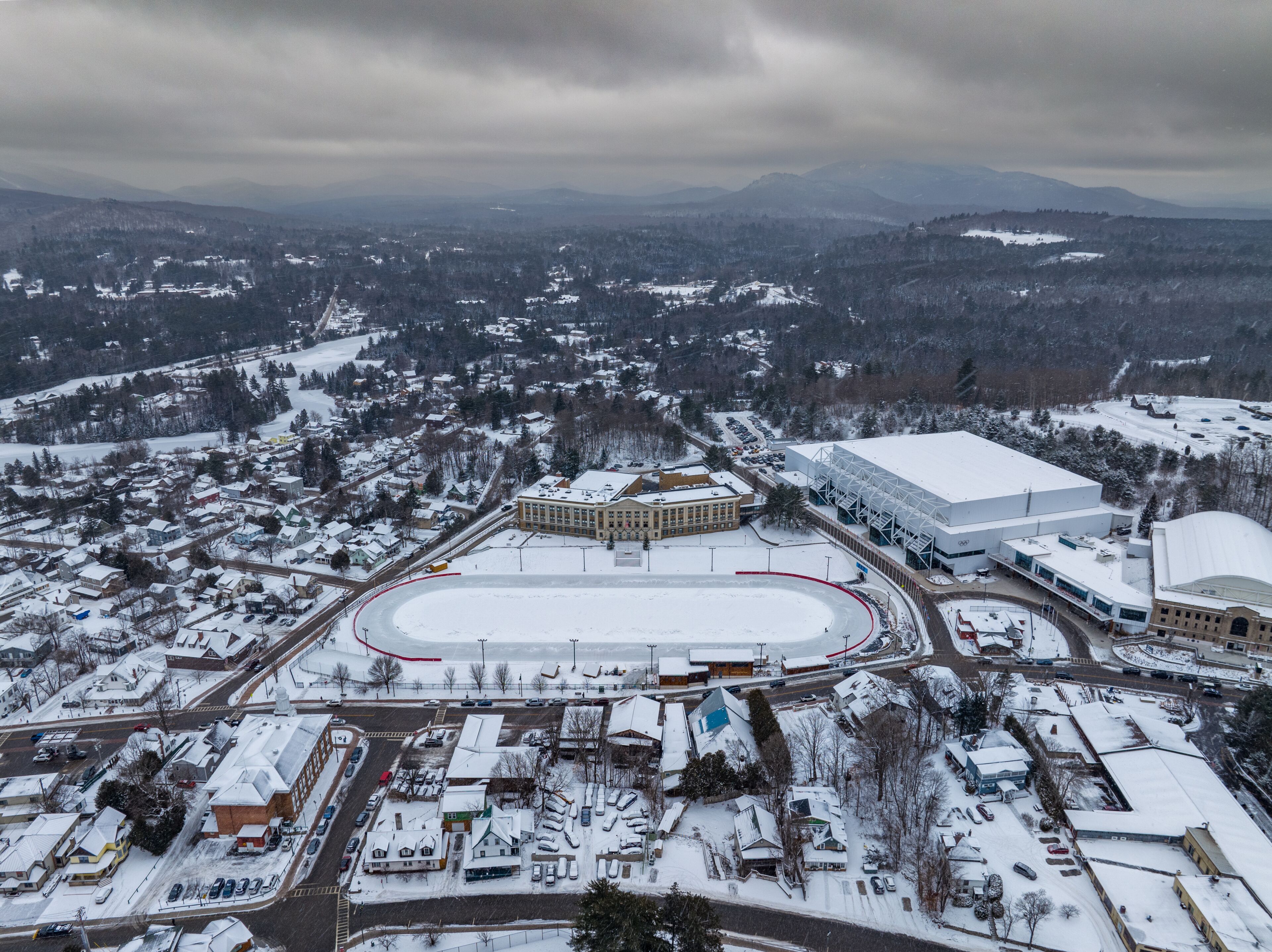 Uma cidade coberta de neve, com um estádio grande e edifícios ao redor.