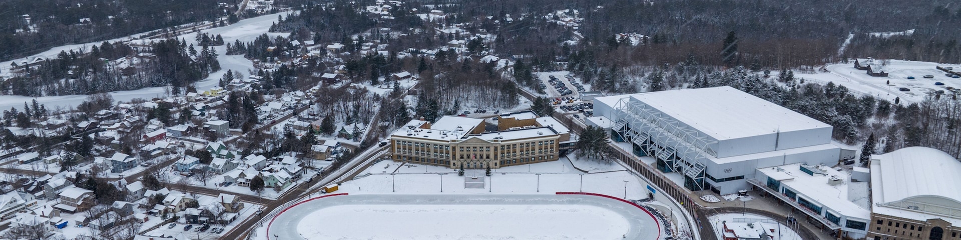 Uma cidade coberta de neve, com um estádio grande e edifícios ao redor.