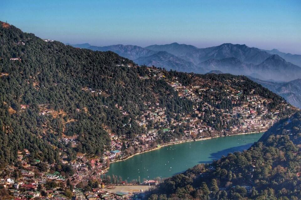 Paisagem montanhosa com um lago e uma cidade situada entre as colinas.