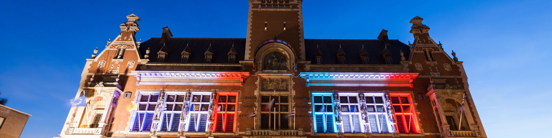 Um edifício histórico com uma torre imponente e luzes coloridas na fachada.