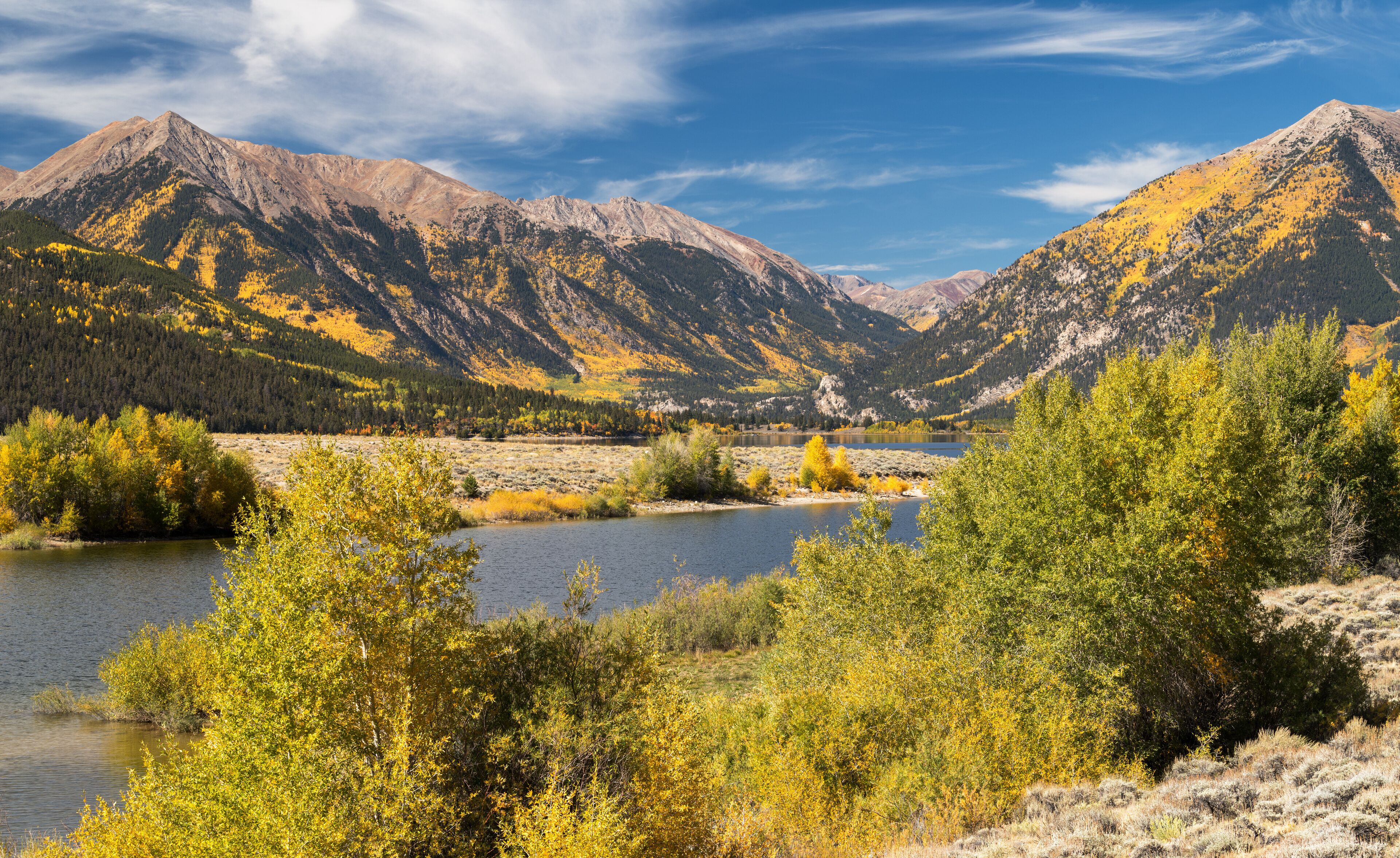 Paisagem montanhosa com um lago e árvores com tons de outono.