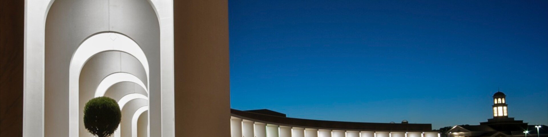 Um edifício com várias arcadas e uma torre ao fundo.