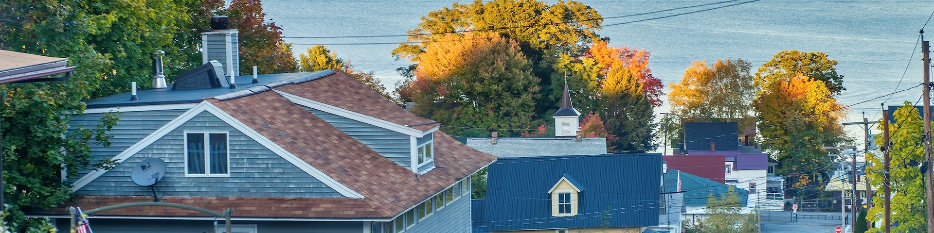 Um bairro residencial com casas, cerca branca e um lago ao fundo.