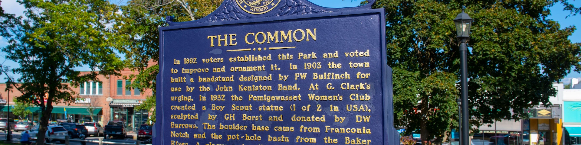Placa histórica em um parque, com texto que detalha sua história.