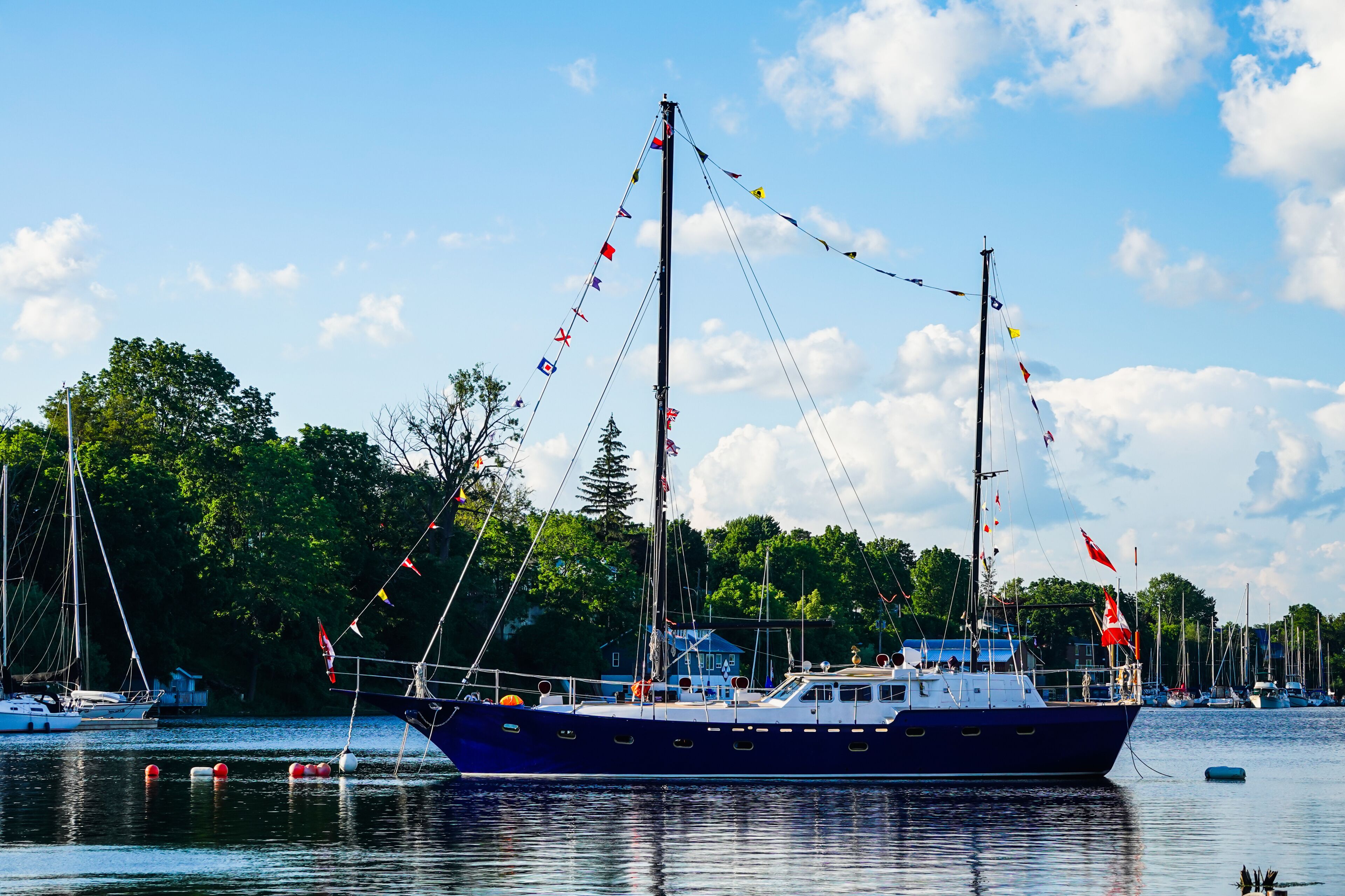 Um grande navio azul atracado em um porto, com várias bandeiras hasteadas no mastro.