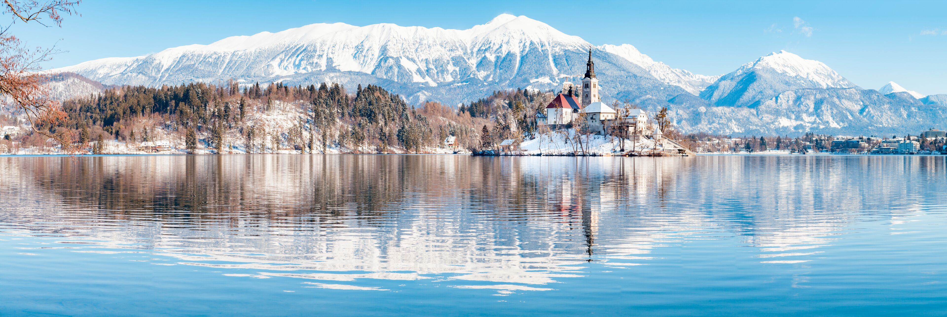 Cordilheira coberta de neve, uma igreja e um lago tranquilo.