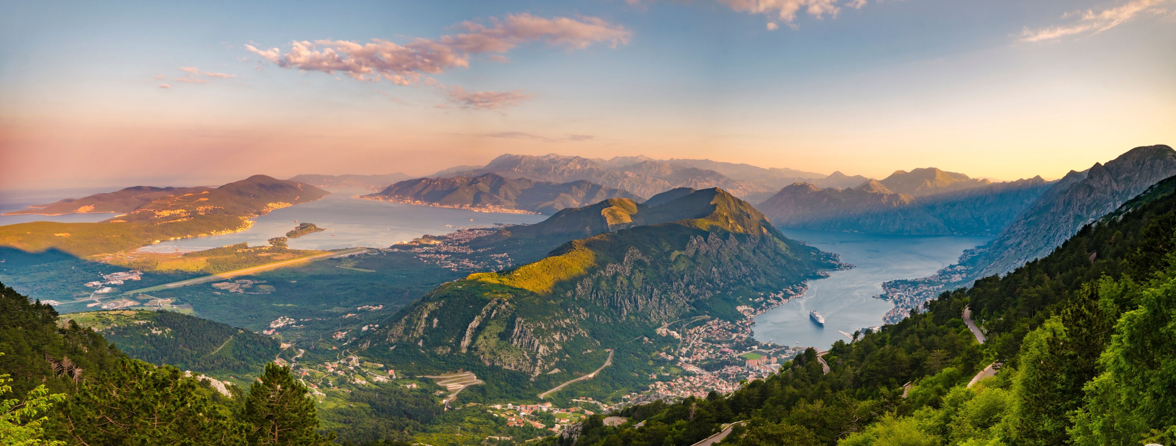 Paisagem montanhosa com um vale, um rio e uma cidade ao longe.