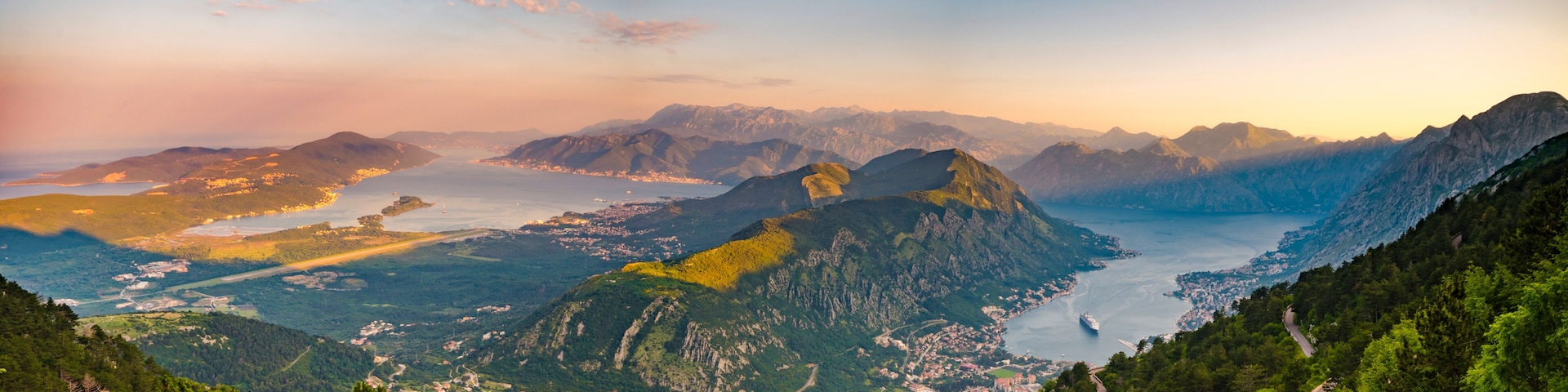 Paisagem montanhosa com um vale, um rio e uma cidade ao longe.
