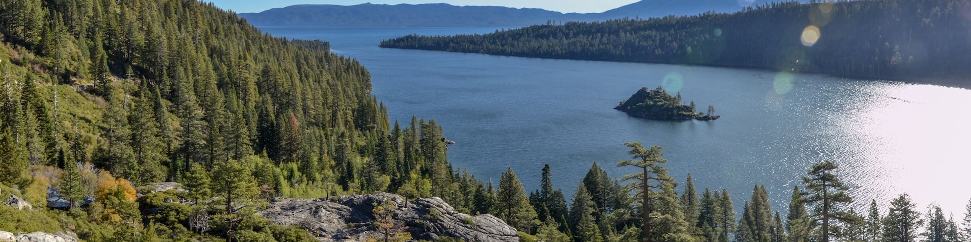 Um lago rodeado por florestas densas e montanhas.