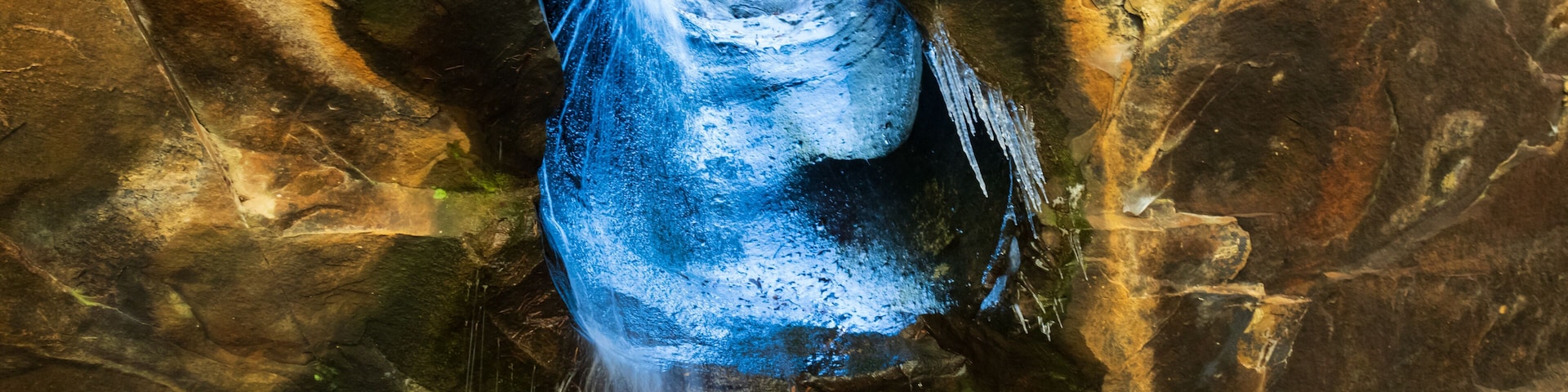 Uma fonte azul com uma cascata em um recinto rochoso.
