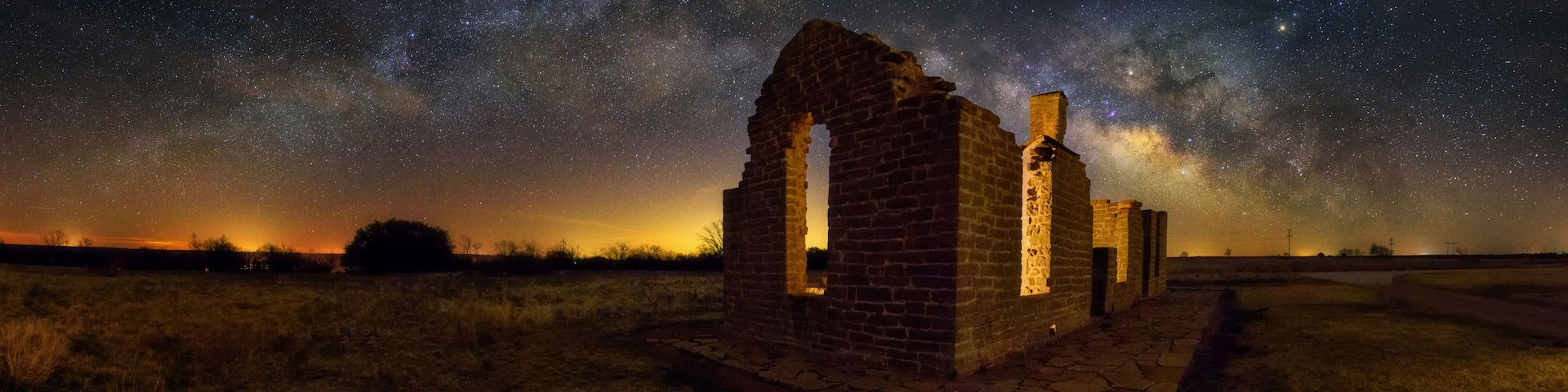 Ruínas de tijolos históricos sob um céu estrelado, com a Via Láctea visível.