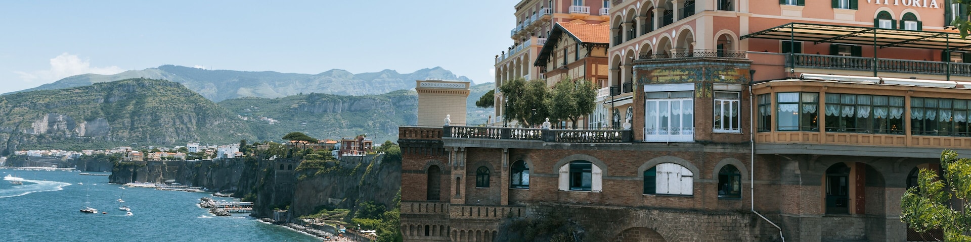 Uma cidade costeira com um porto de iates, edifícios históricos e um cenário montanhoso.