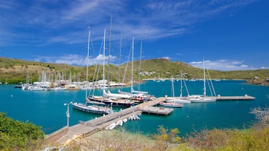 Uma marina com barcos à vela atracados, rodeada por colinas e águas azuis cristalinas.
