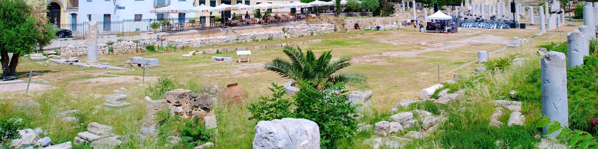Ruínas antigas com colunas de pedra, um templo e edifícios tradicionais.