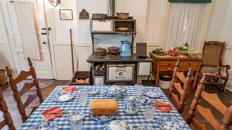 Uma cozinha antiga com toalha quadriculada, porcelana antiga e um fogão Reliant Windsor.