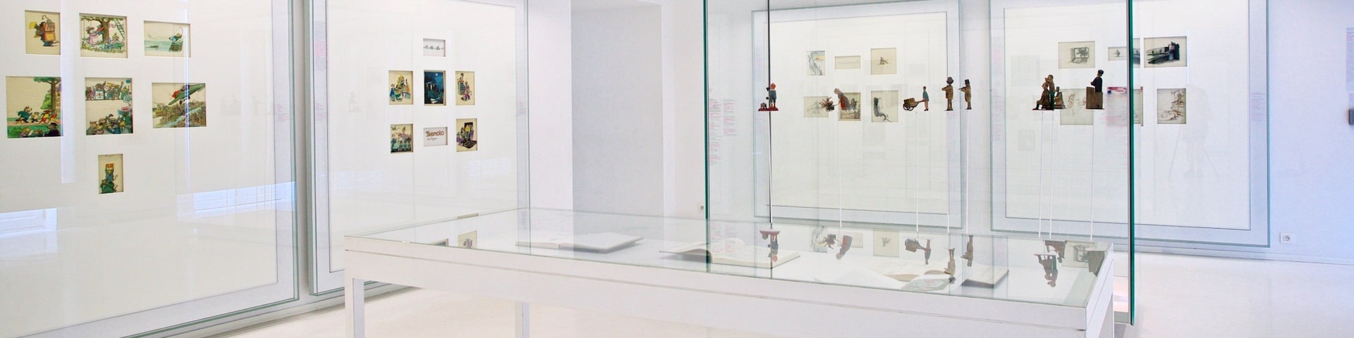 Uma galeria de arte com vitrines de vidro que exibem diversas obras.