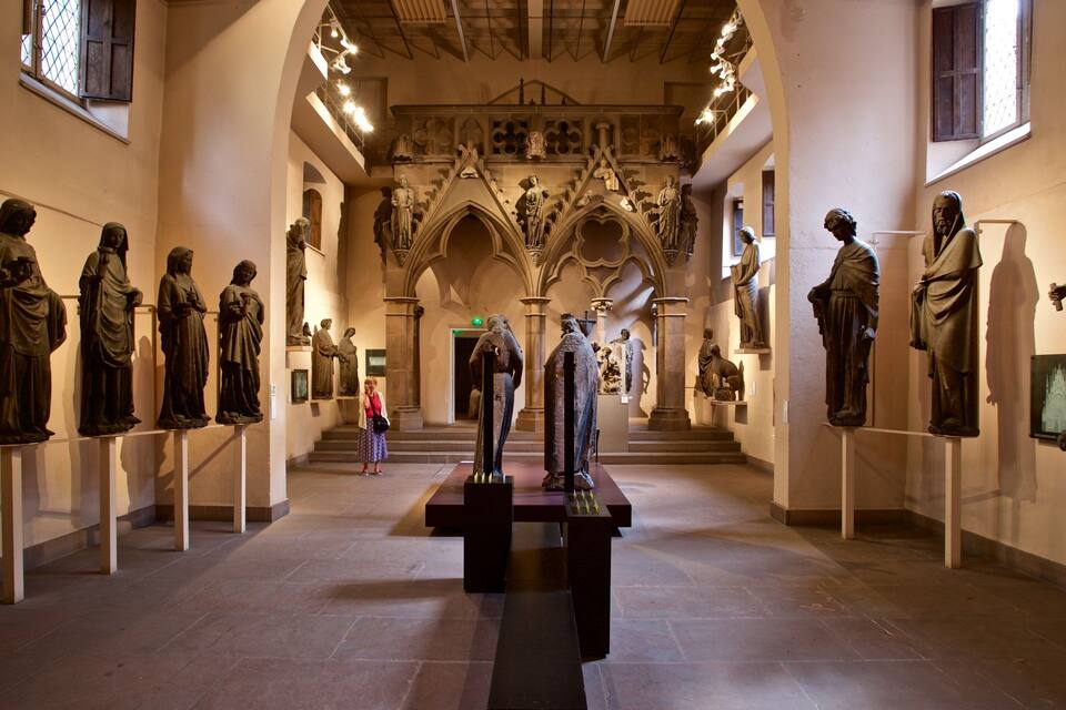 Interior de museu com arquitetura gótica, com estátuas e um altar central.